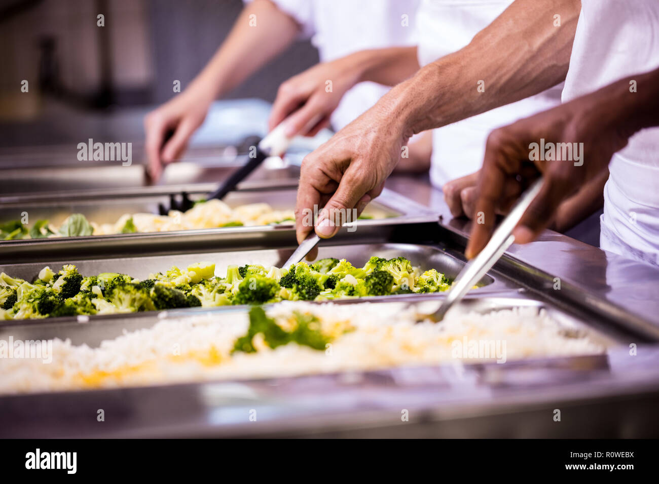 Chefs standing at serving tray of food in kitchen Stock Photo - Alamy