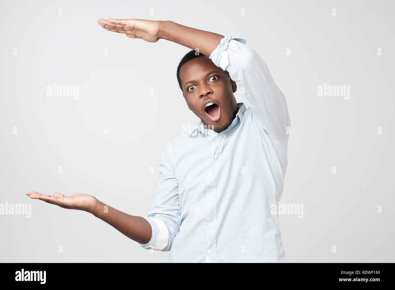Afro american man gesturing with hands showing big and large size sign ...