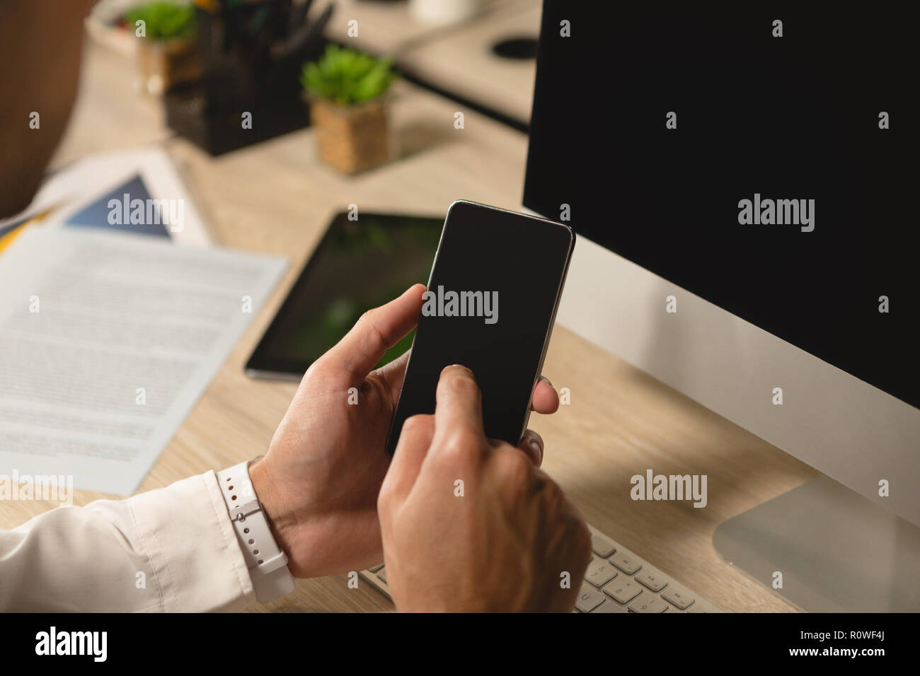 Executive using mobile phone at desk Stock Photo - Alamy