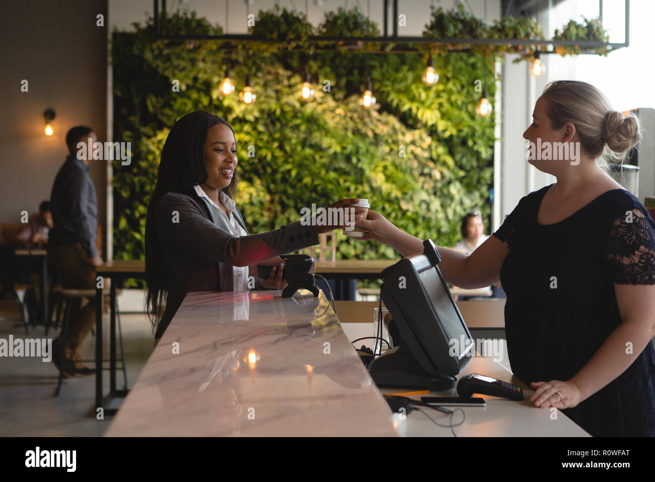 Waitress serving coffee to female executive at counter Stock Photo - Alamy