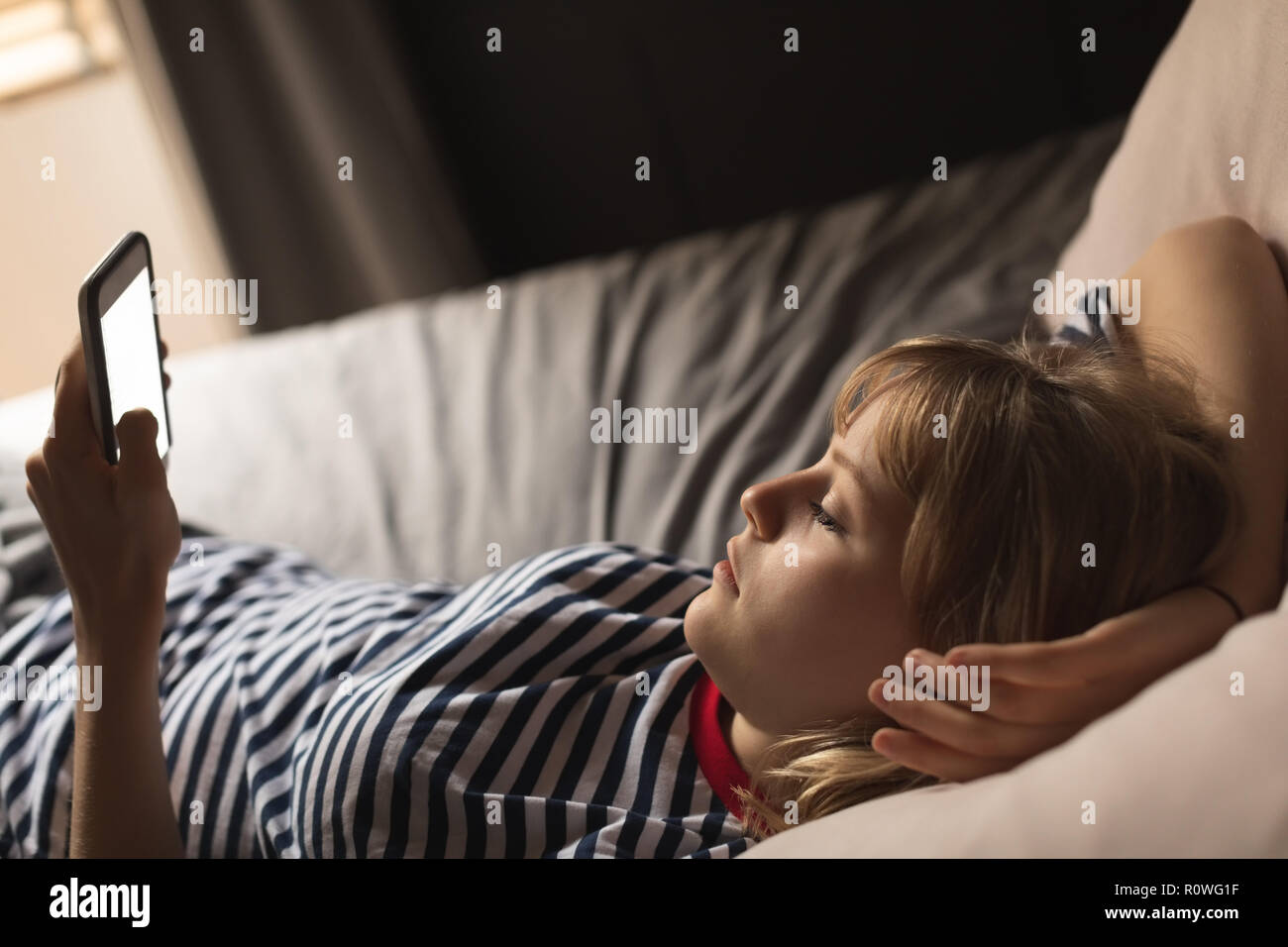 Woman using mobile phone on bed in bedroom Stock Photo - Alamy