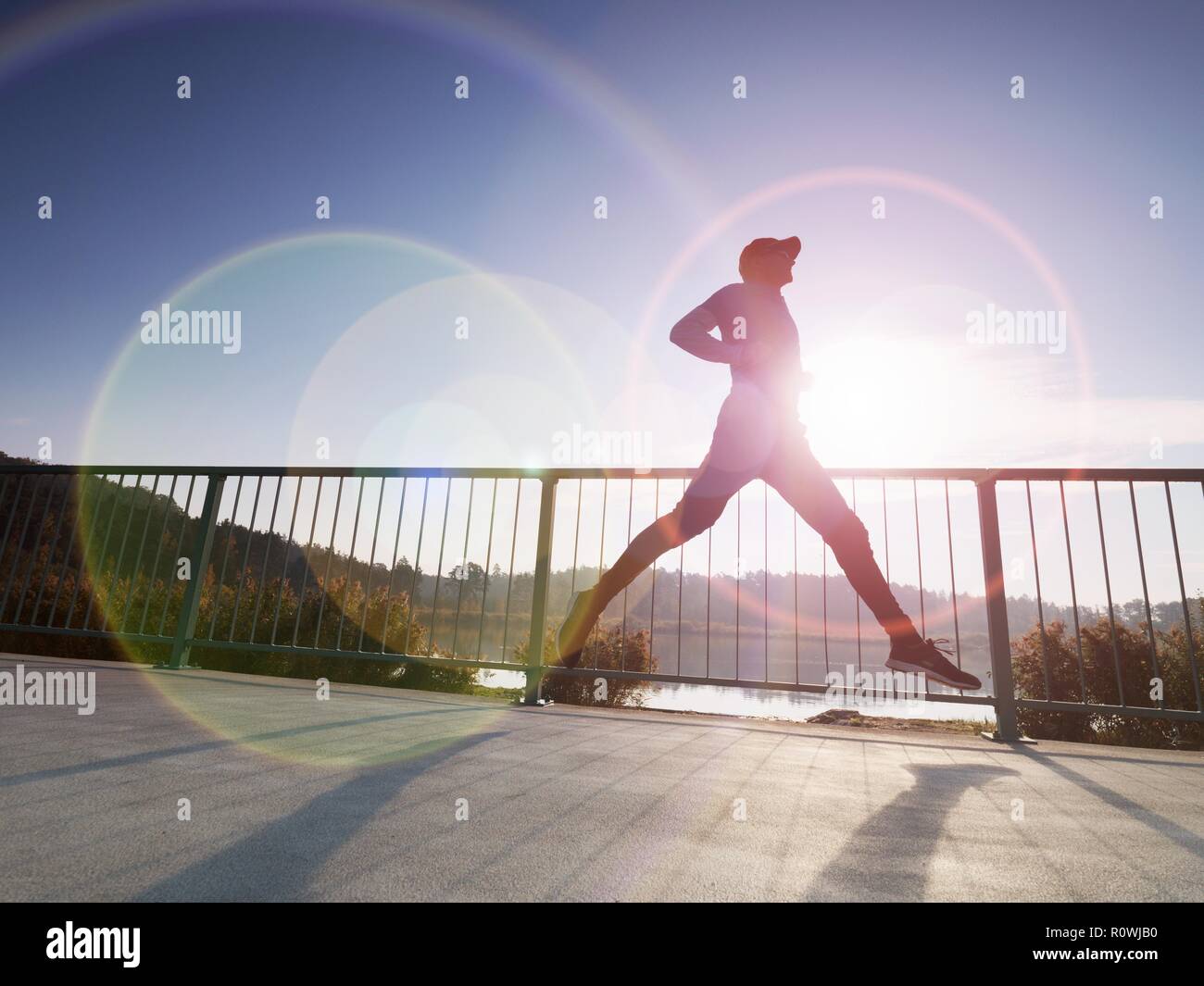 Full section view of fit slim man running on boardwalk. He is in sports ...