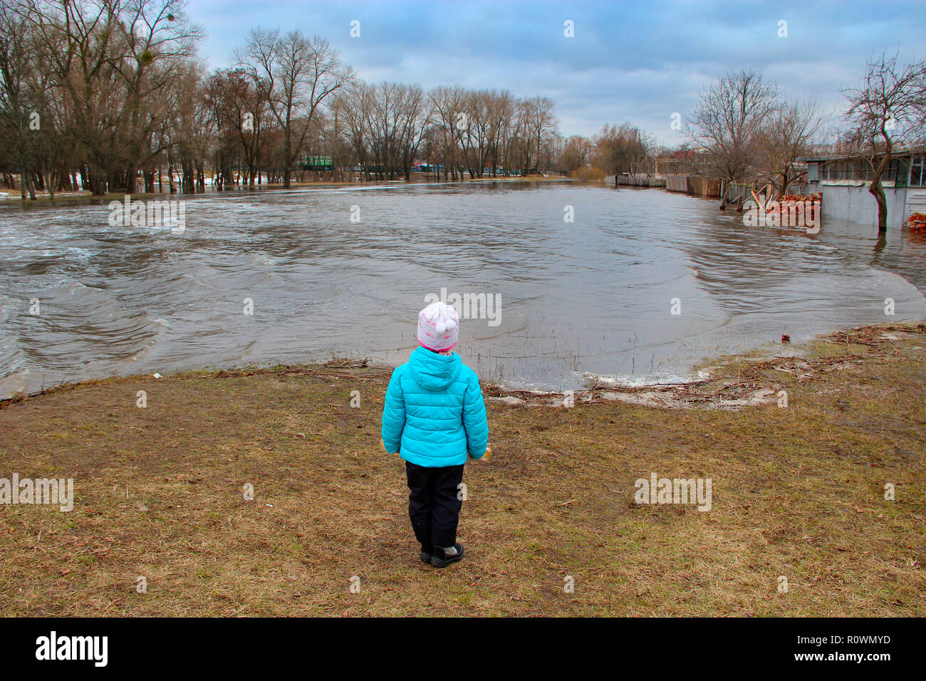Child watching river flooding in city after melting snow in spring ...