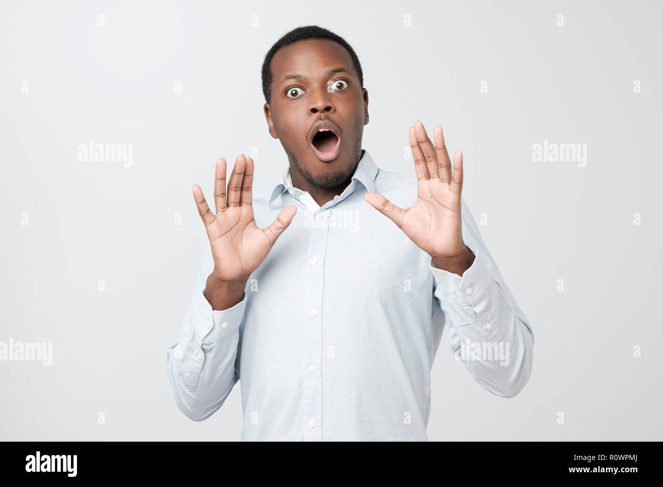African man having stunned and shocked look listening to friends story ...