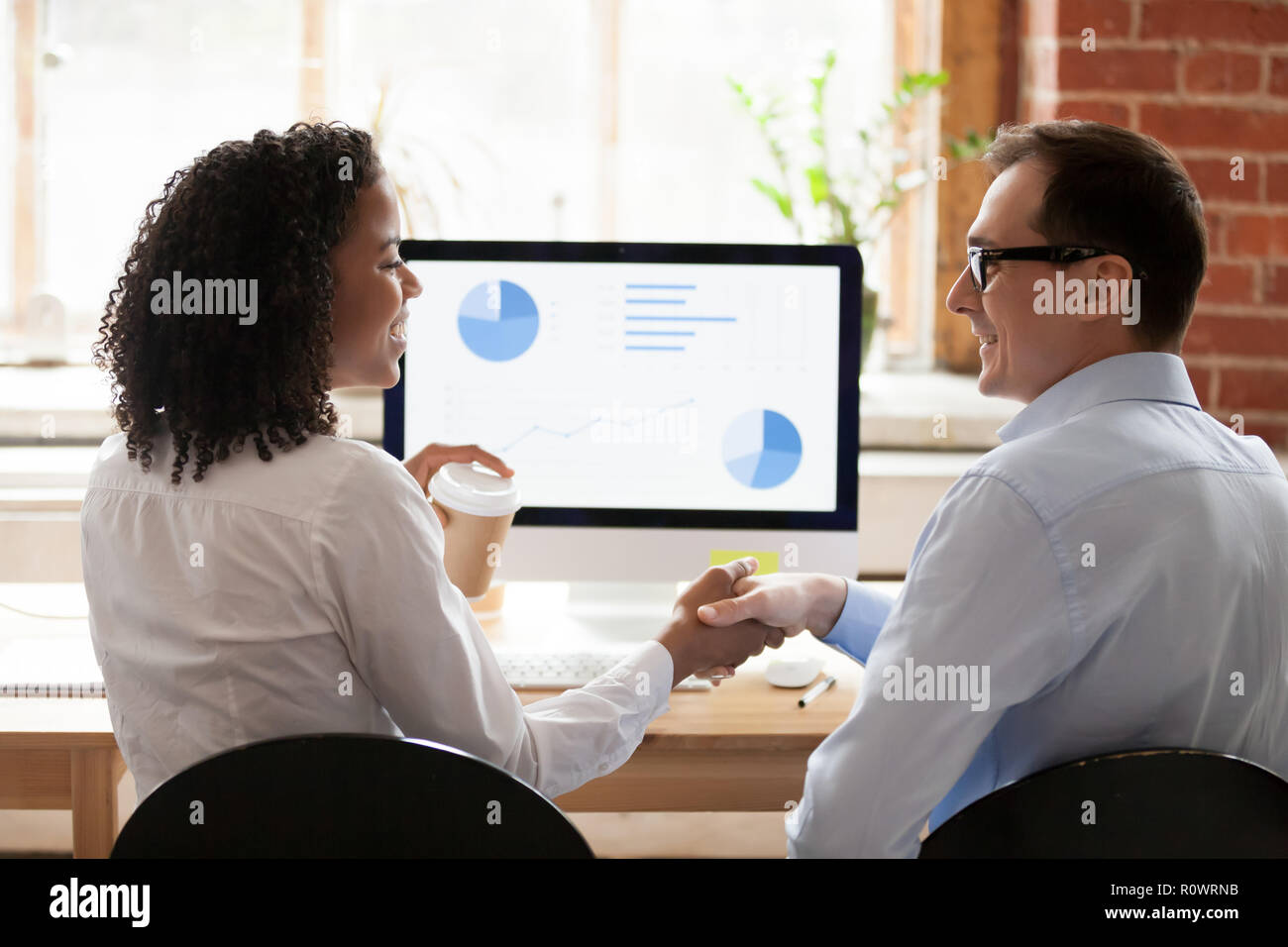 Diverse employees handshake working together at pc in office Stock ...