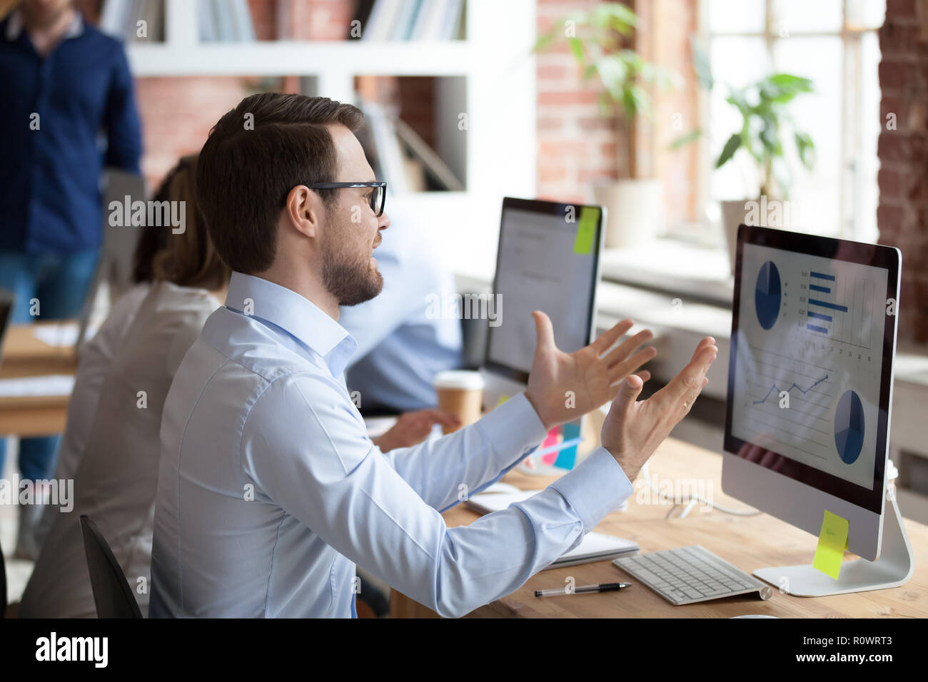 Nervous male employee gesturing angry about computer problem Stock ...