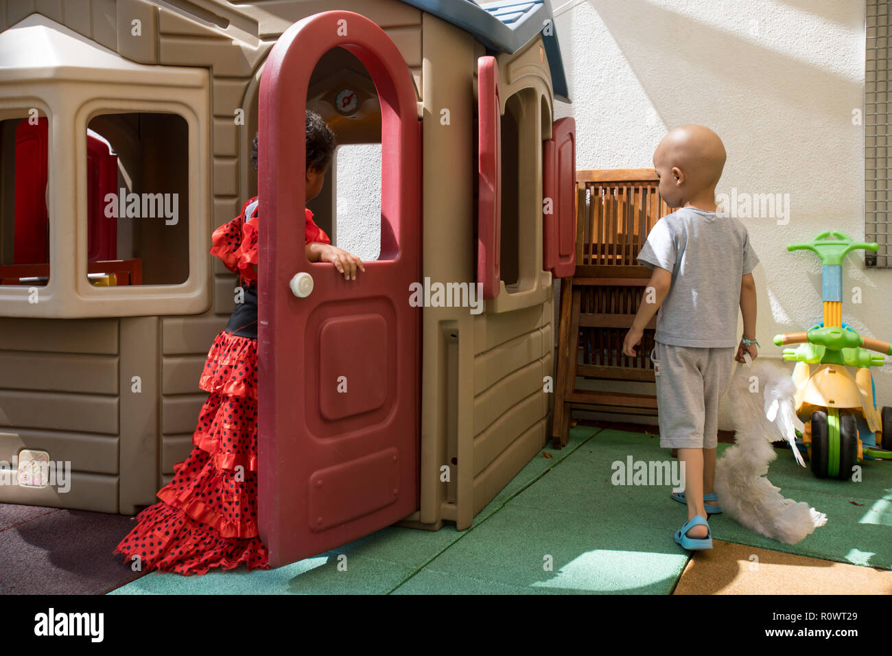 Young boy and girl with cancer playing in toy house on playground Stock ...