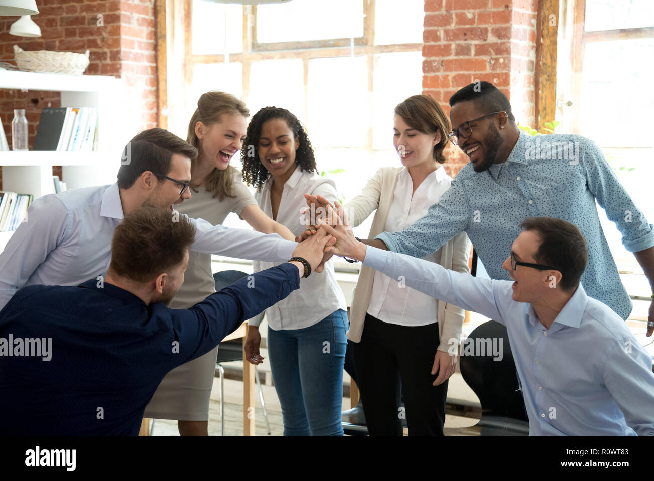 Excited diverse workers join hands at teambuilding activity Stock Photo ...