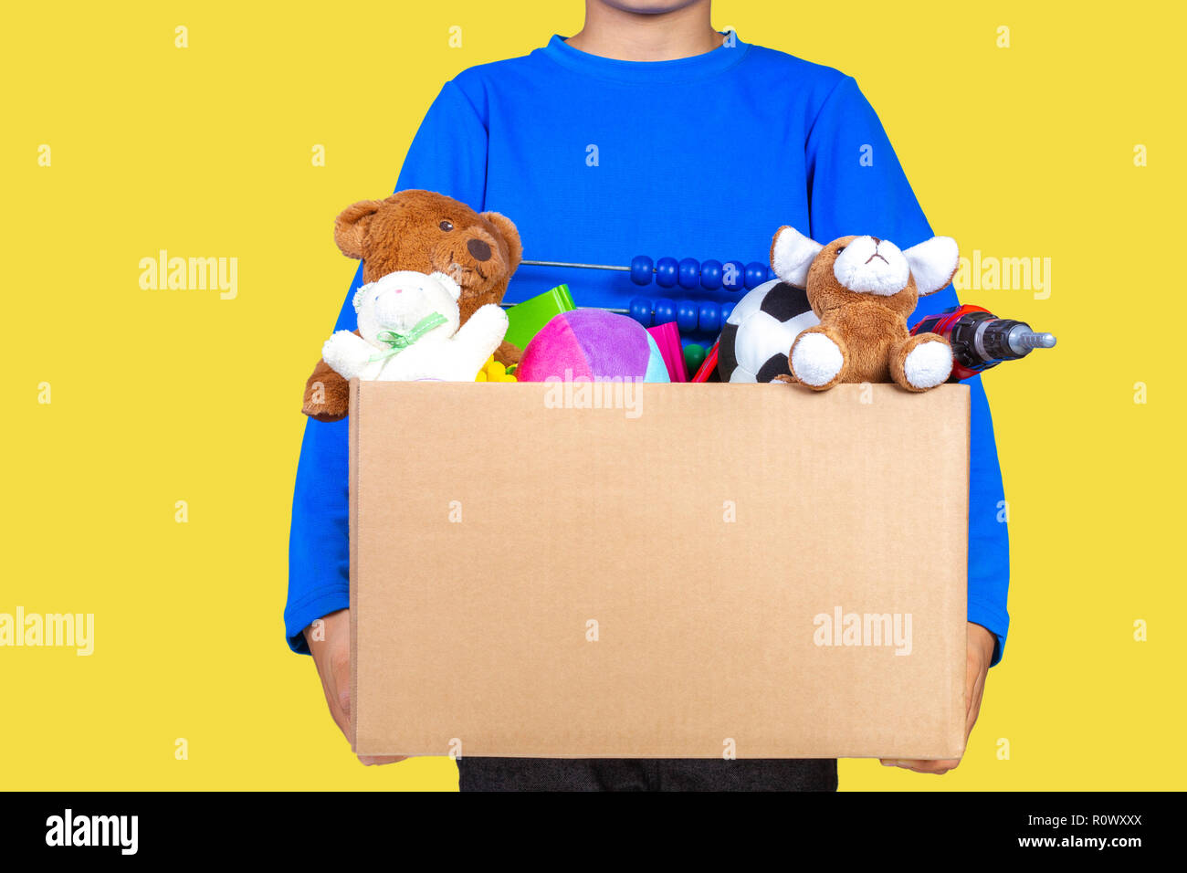 Donation concept. Kid holding donate box with clothes, books, school ...