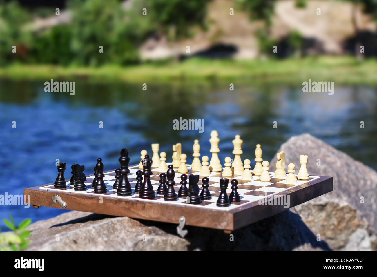 Chess board with chess pieces on rock with river embankment background ...