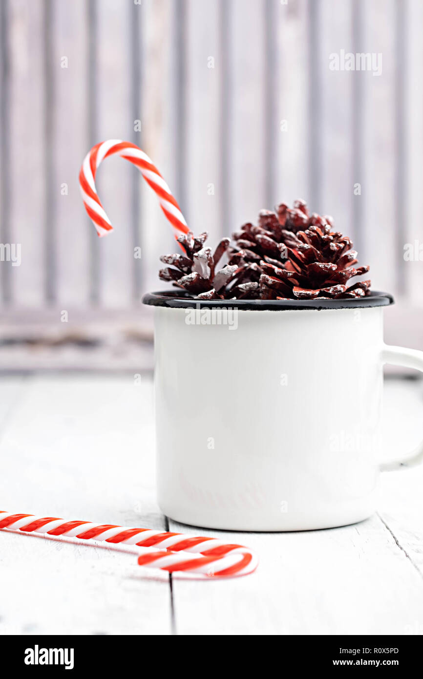 Christmas candy cane sticks in white tin cup with fir cones. Light ...