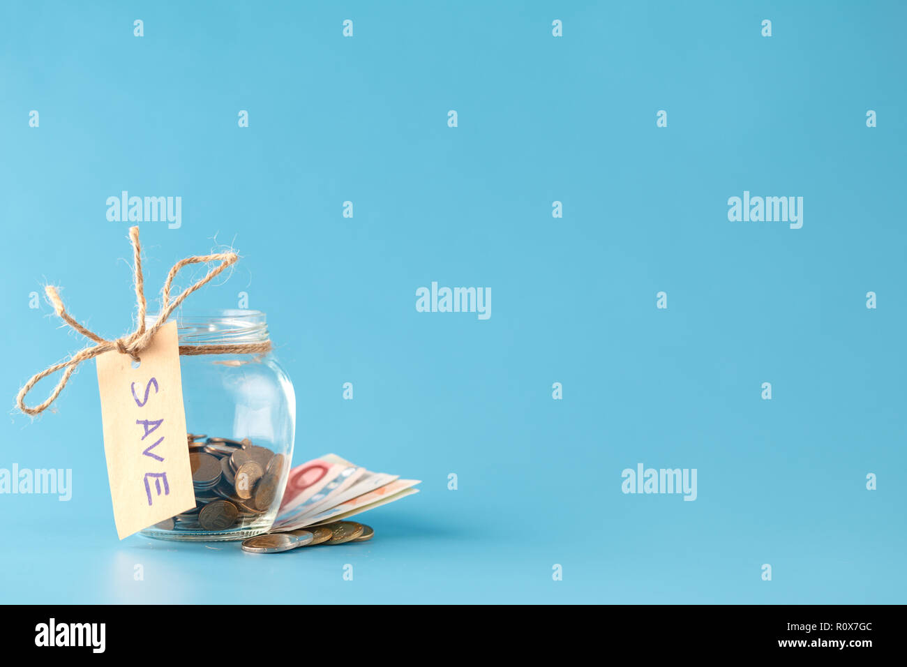 Coins in savings jar full of money Stock Photo - Alamy