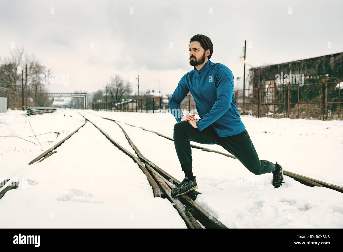 Active young man stretching and doing exercises in the public place ...