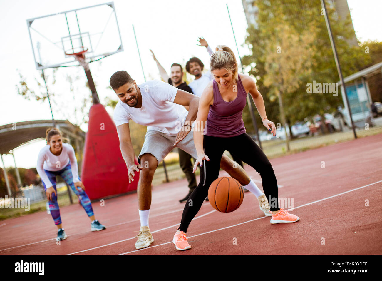 Group of multiethnic young people playing basketball on court Stock ...