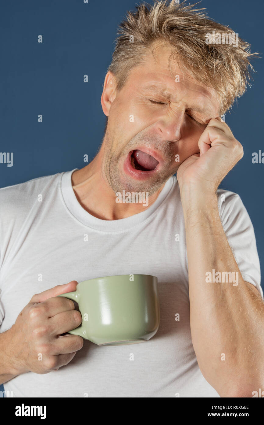 Sleepy man with a mug of coffee and a towel Stock Photo - Alamy