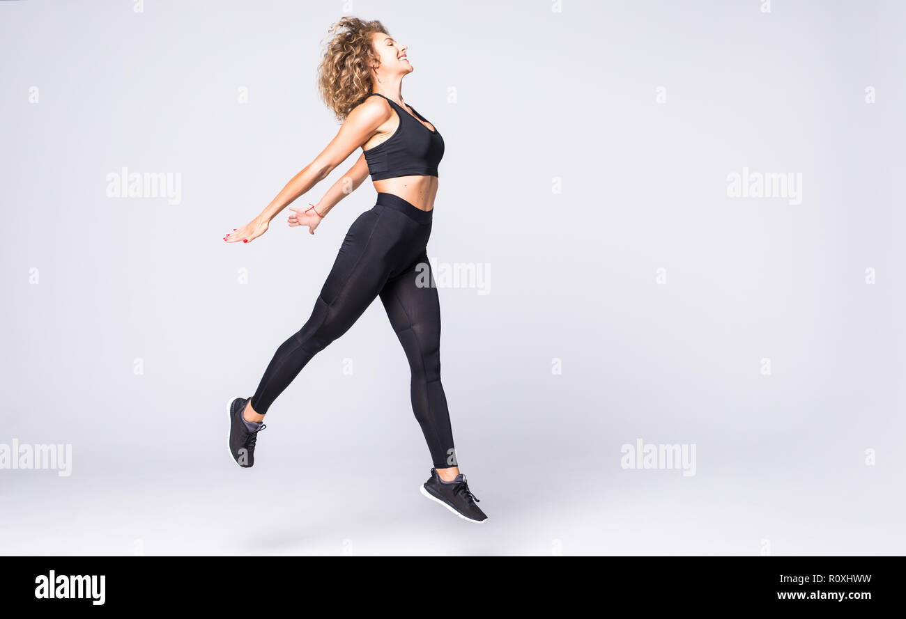 Side view of a sporty young woman jumping isolated on white background ...