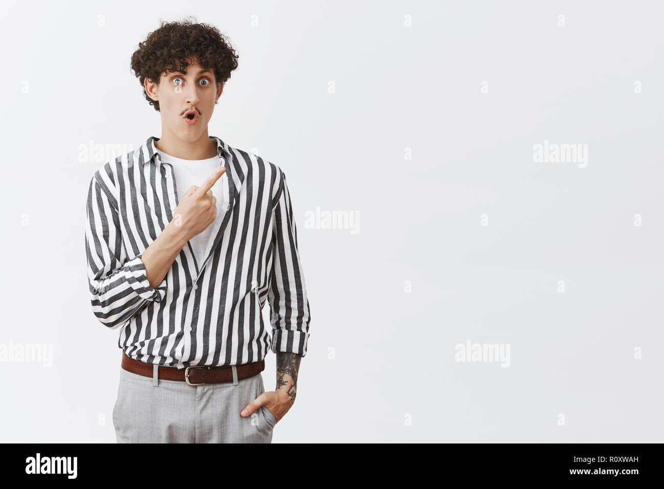 Indoor shot of impressed and amazed jewish curly-haired guy with ...