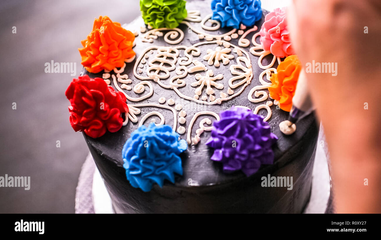 Step by step. Baker piping colorful buttercreal italian icing on a top ...