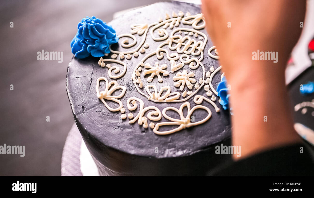 Step by step. Baker piping colorful buttercreal italian icing on a top ...