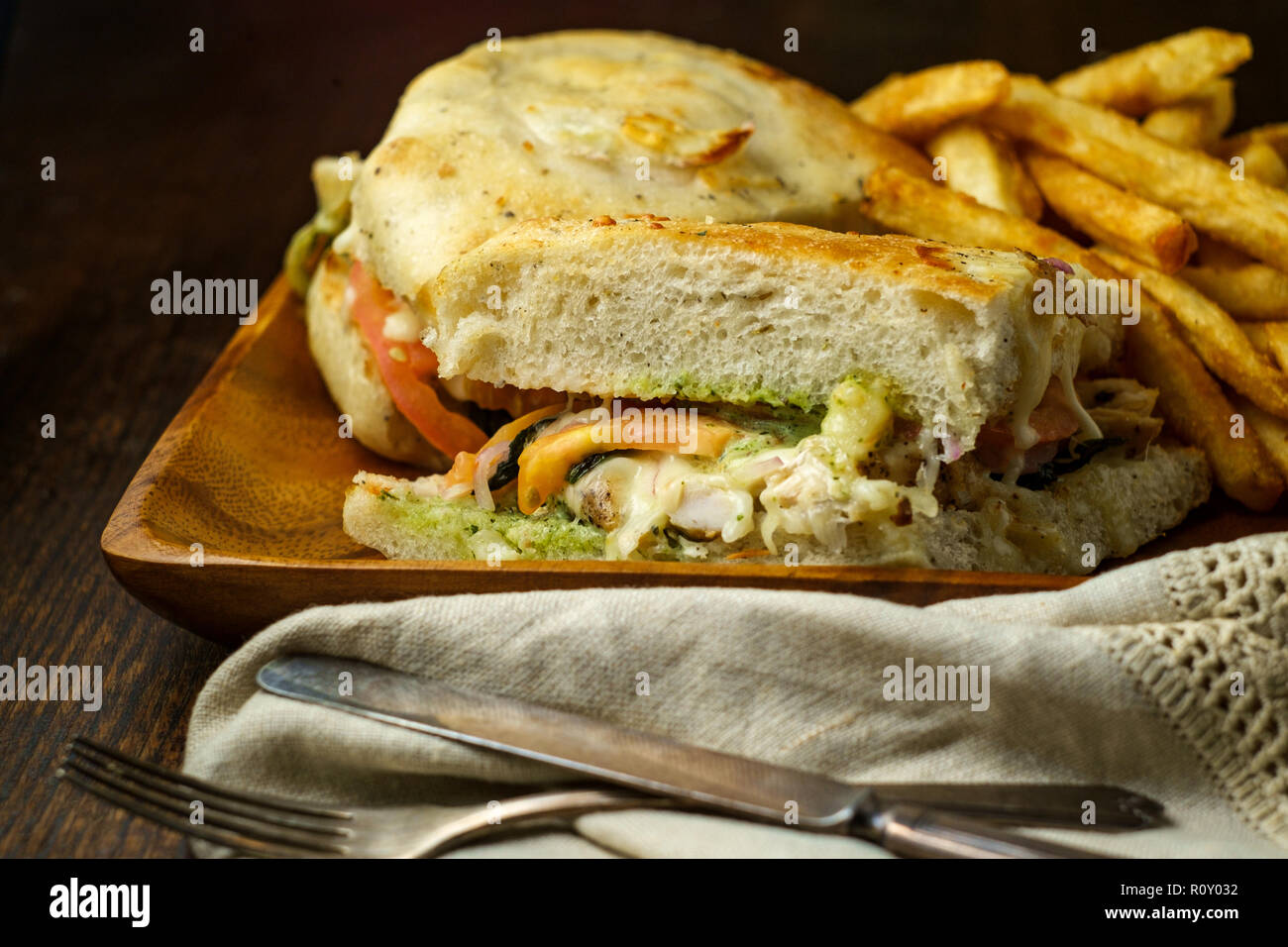 Grilled chicken panini with fresh crispy steak fries on rustic wooden ...