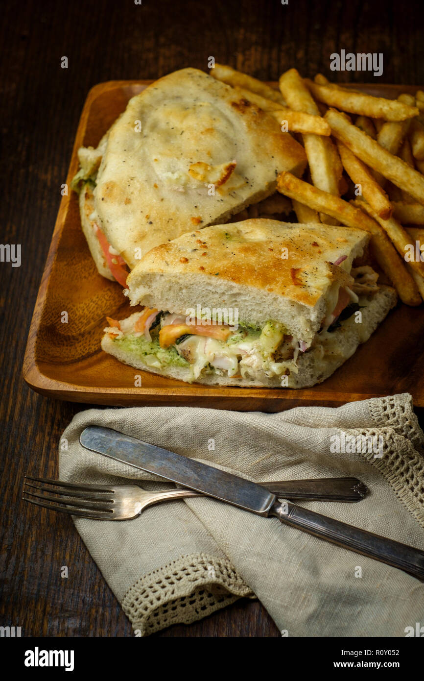 Grilled chicken panini with fresh crispy steak fries on rustic wooden ...