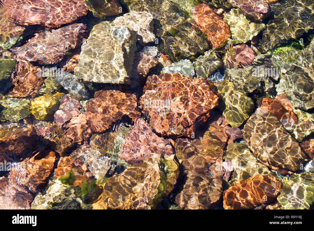 Crystal clear clean shallow water reveals wonderful colours on pebbles ...