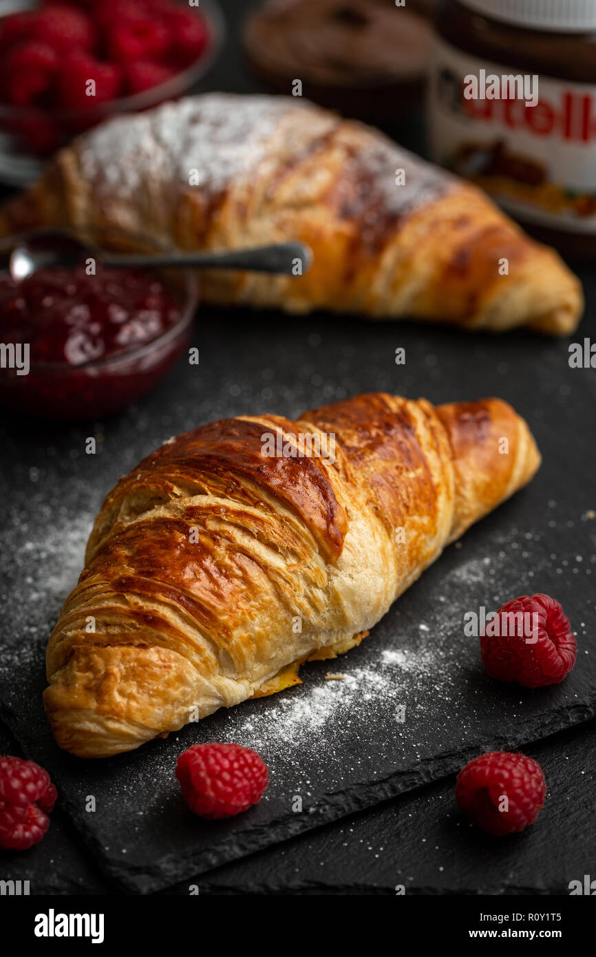 Croissants with icing sugar surrounded with raspberries, raspberry jam ...