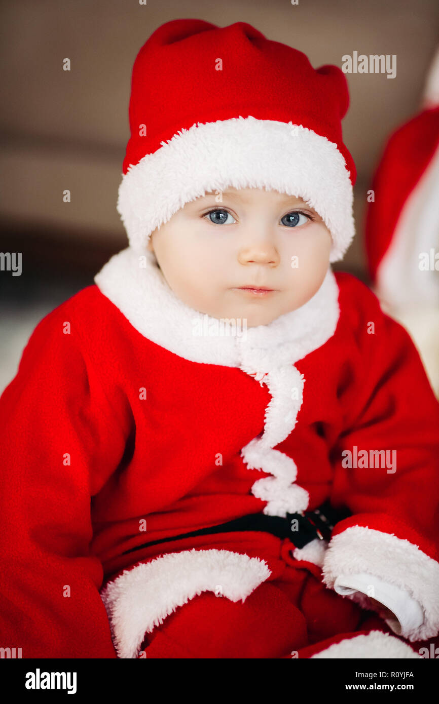 Little Santa boy in red suite sitting in big arm chair near Christmas ...