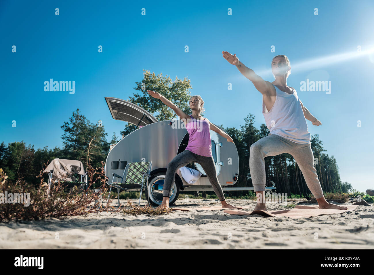Healthy girlfriend and boyfriend standing in warrior pose doing yoga ...