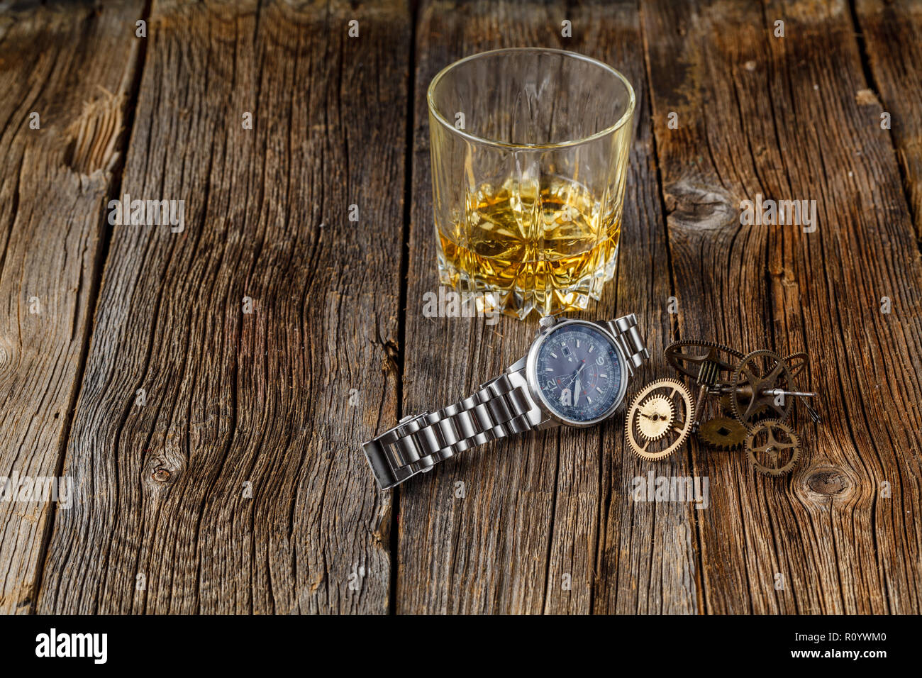 Whiskey and clock gears on wooden table Stock Photo - Alamy