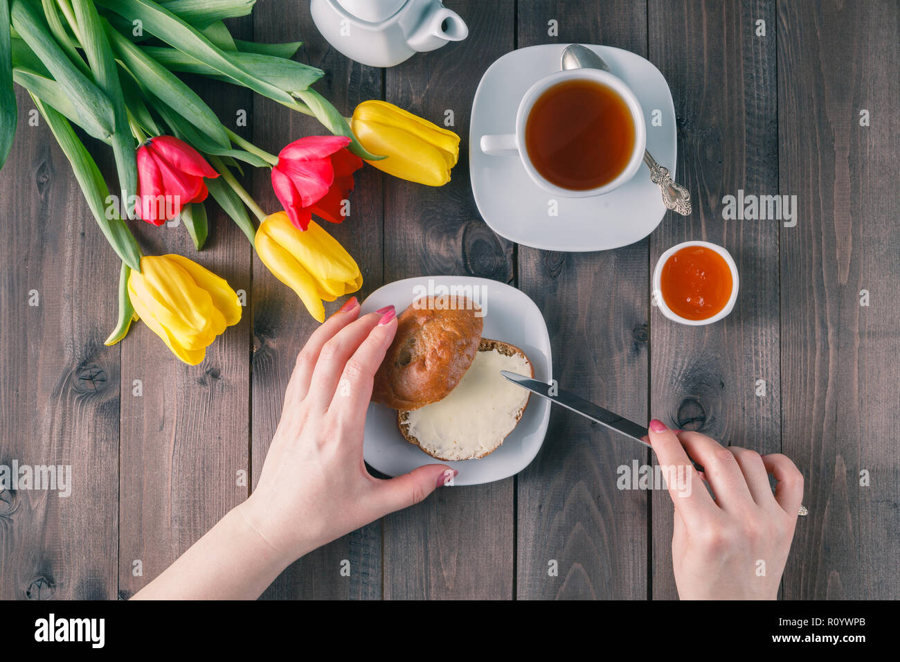 Holiday breakfast with flowers, woman buttering bread Stock Photo - Alamy