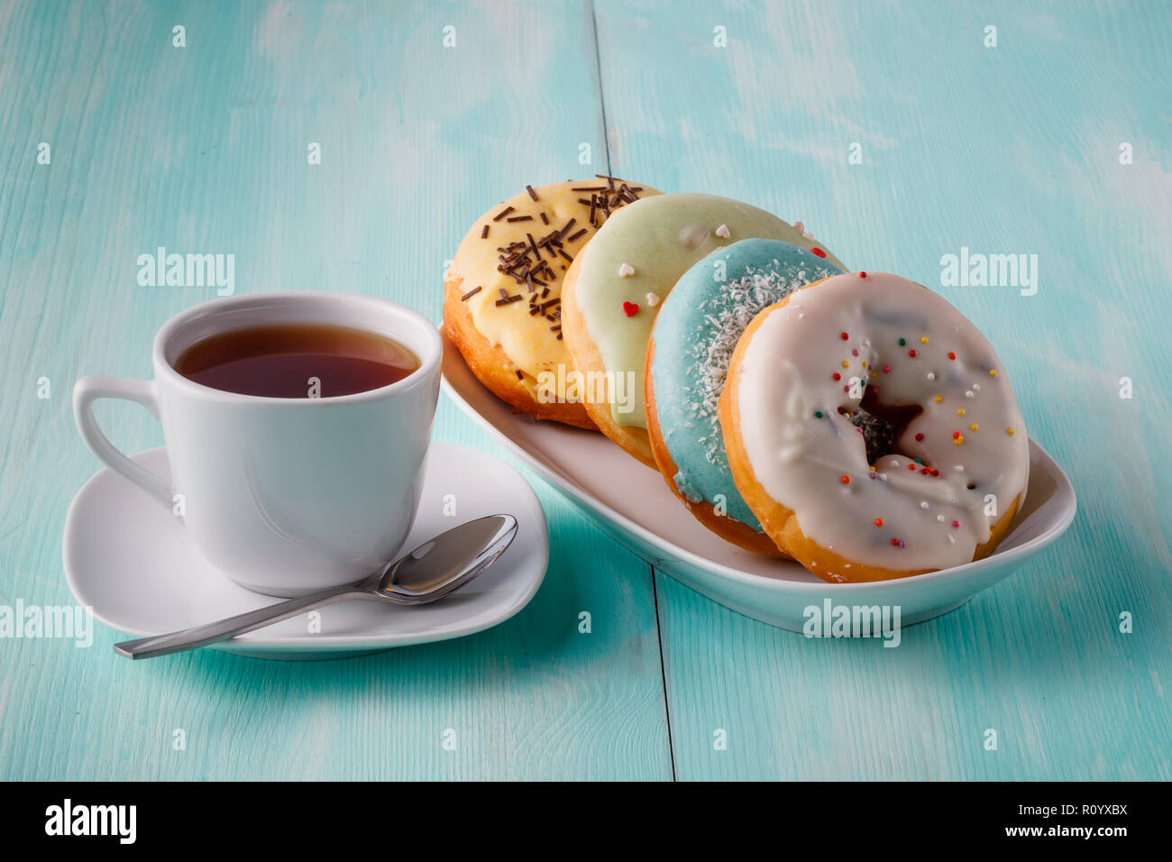Four donuts on old wood table with cup of tea Stock Photo - Alamy