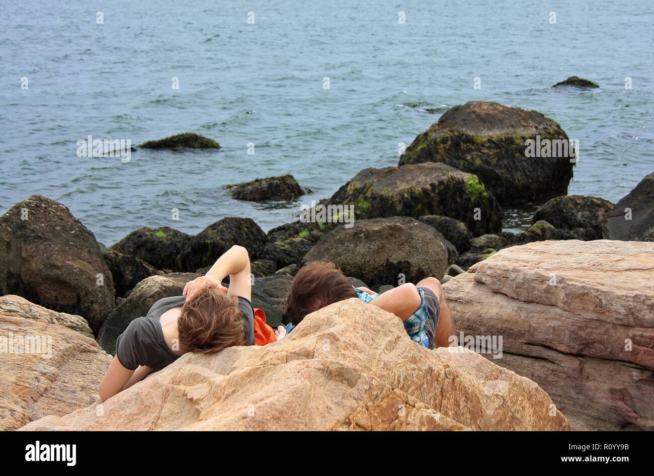 A young couple laying on the rocks talking, thinking, and just enjoying ...