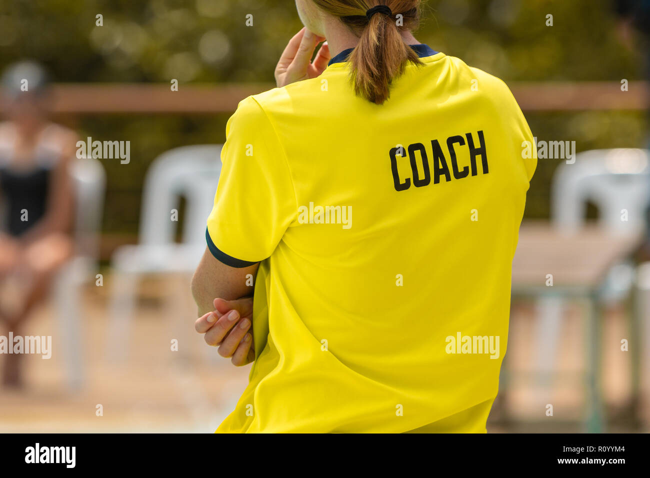 Back View Of Swimming Coaches Wearing Coach Shirt Working Together At