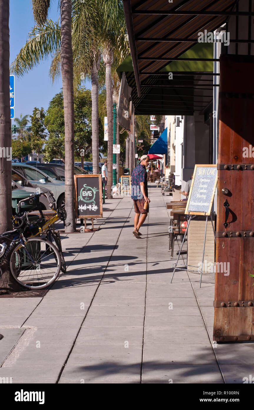 A man walking down the sidewalk next to store fronts in Encinitas ...