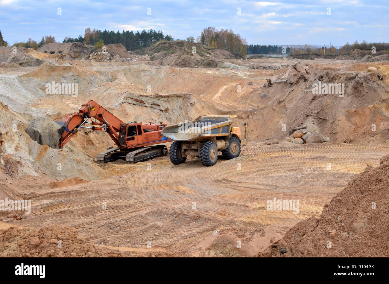 Excavator loading sand into dumper truck. Large quarry dump truck. View ...