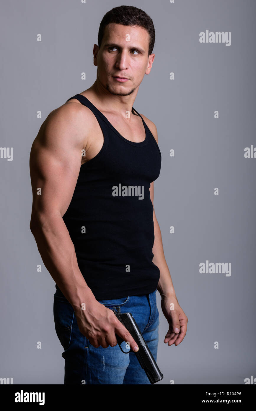 Studio shot of young muscular Persian man standing and thinking Stock ...