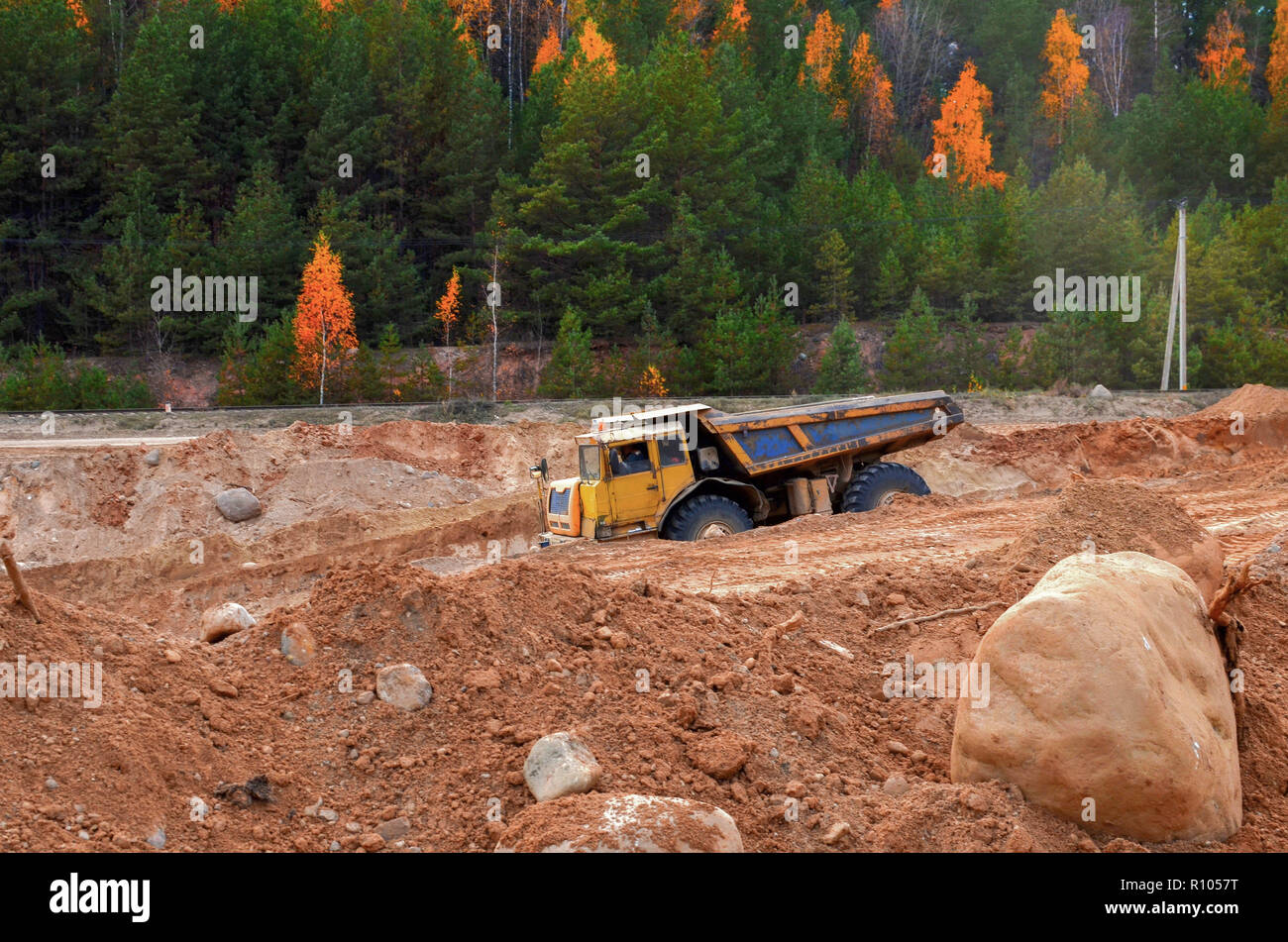 Earth mover loading dumper truck with sand in quarry. Excavator loading ...