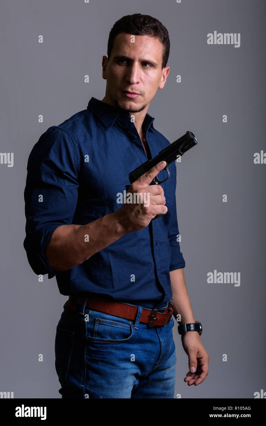 Portrait of serious businessman holding gun while thinking Stock Photo ...