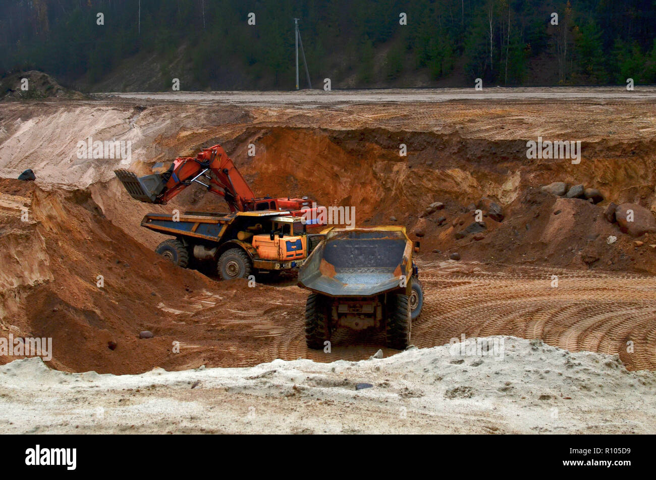 Earth mover loading dumper truck with sand in quarry. Excavator loading ...