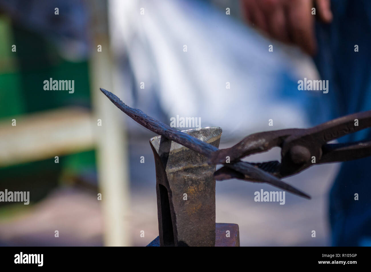 blacksmith performs the forging of hot glowing metal on the anvil ...