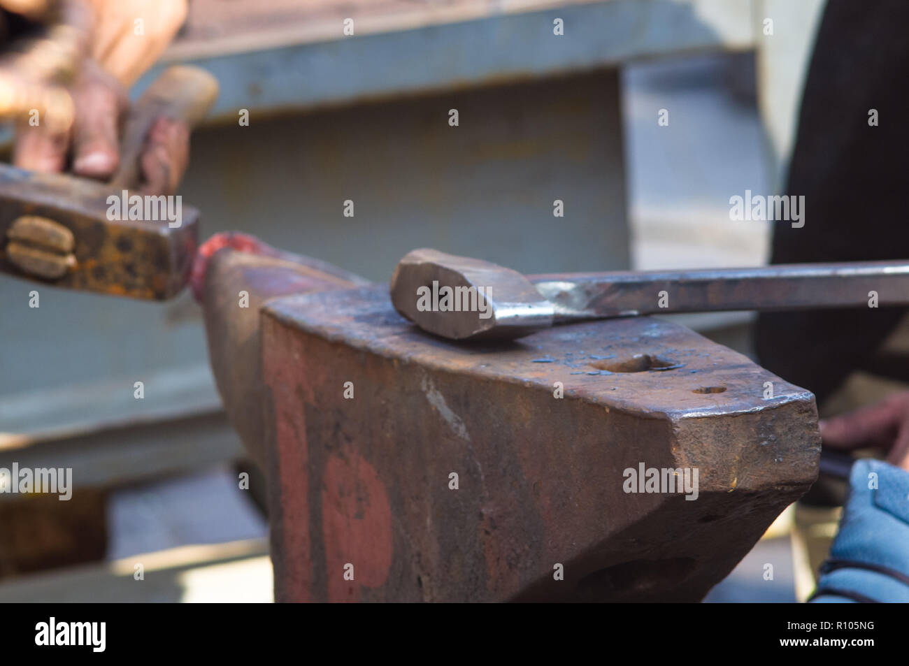 blacksmith performs the forging of hot glowing metal on the anvil ...