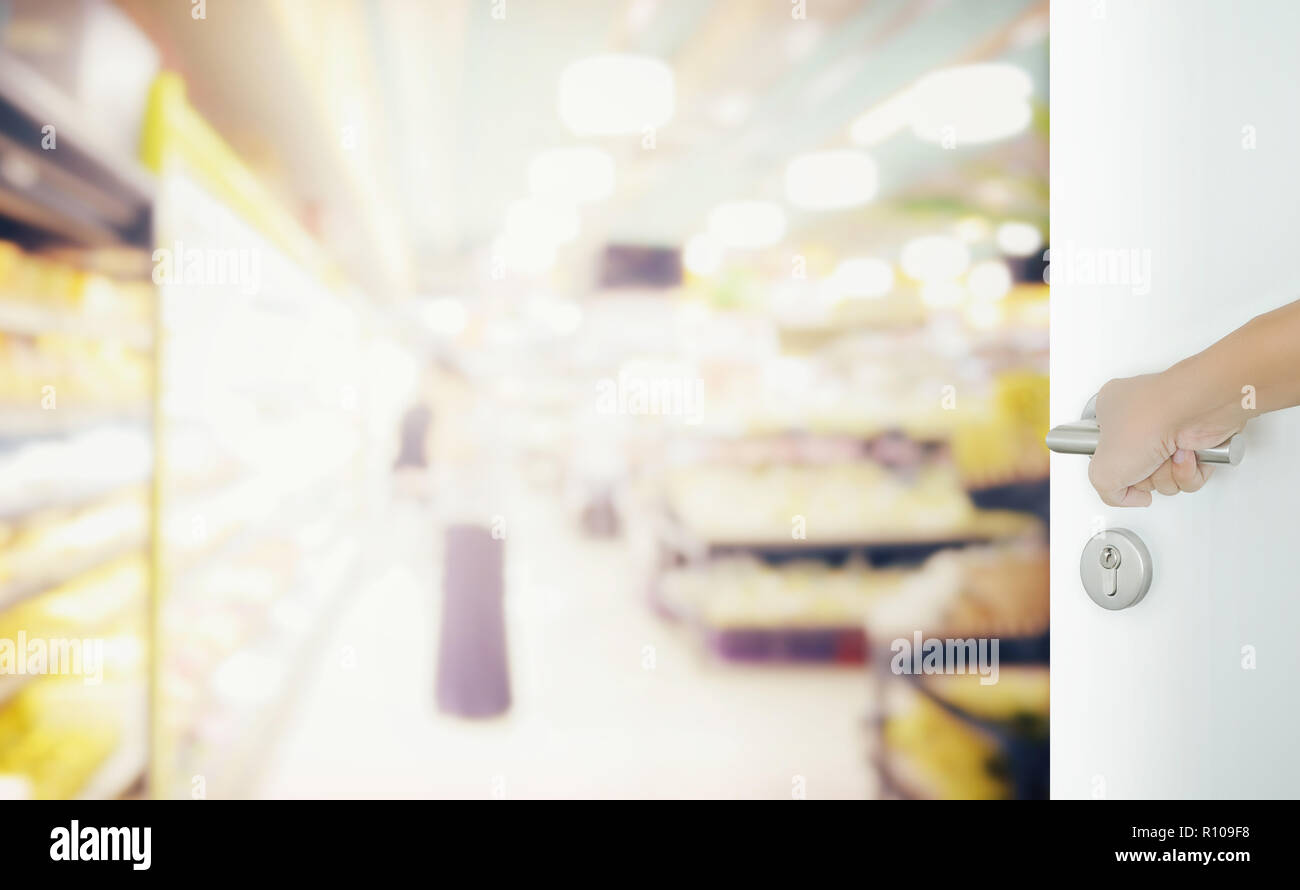 man hand opening white door to supermarket with miscellaneous product ...