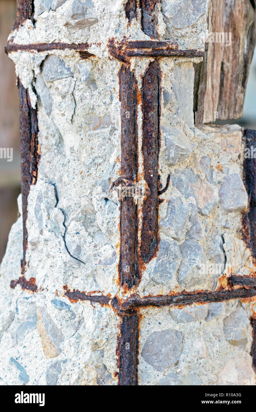 Disintegrated old concrete pillar with damaged and rusty steel frame ...