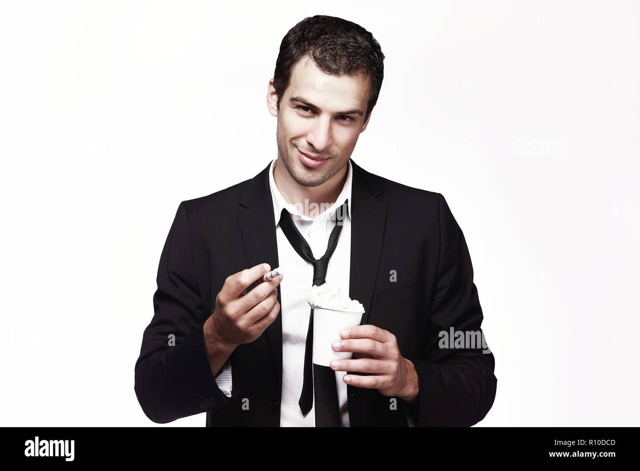 A young guy in a black suit holding a coffee Cup with whipped cream ...