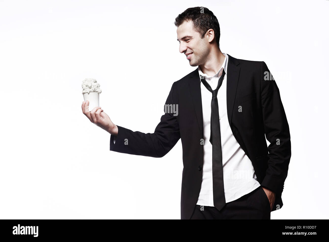 A young guy in a black suit offers a coffee Cup with whipped cream ...