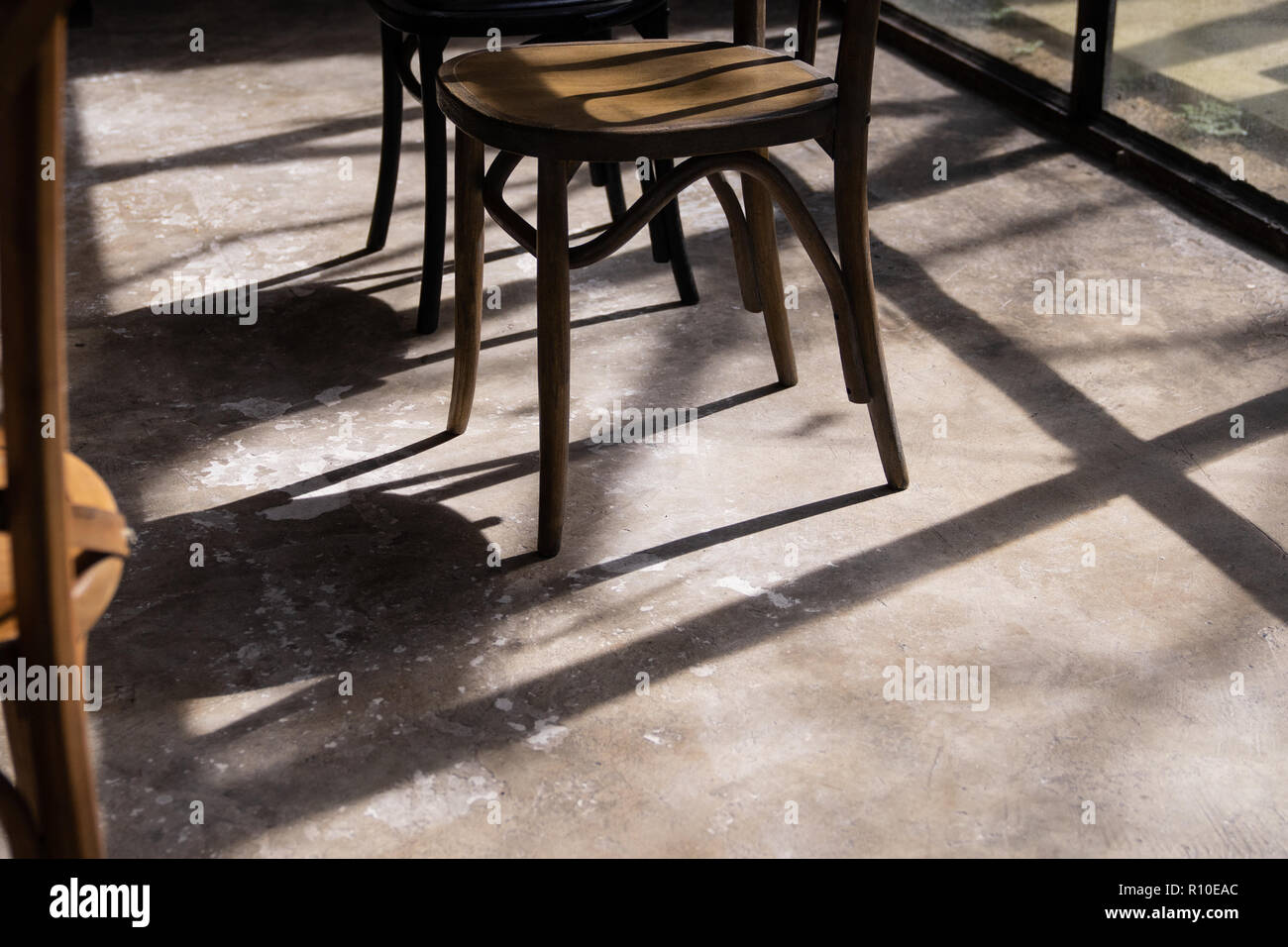 close up wooden chair legs with shadow and light on grunge cement ...
