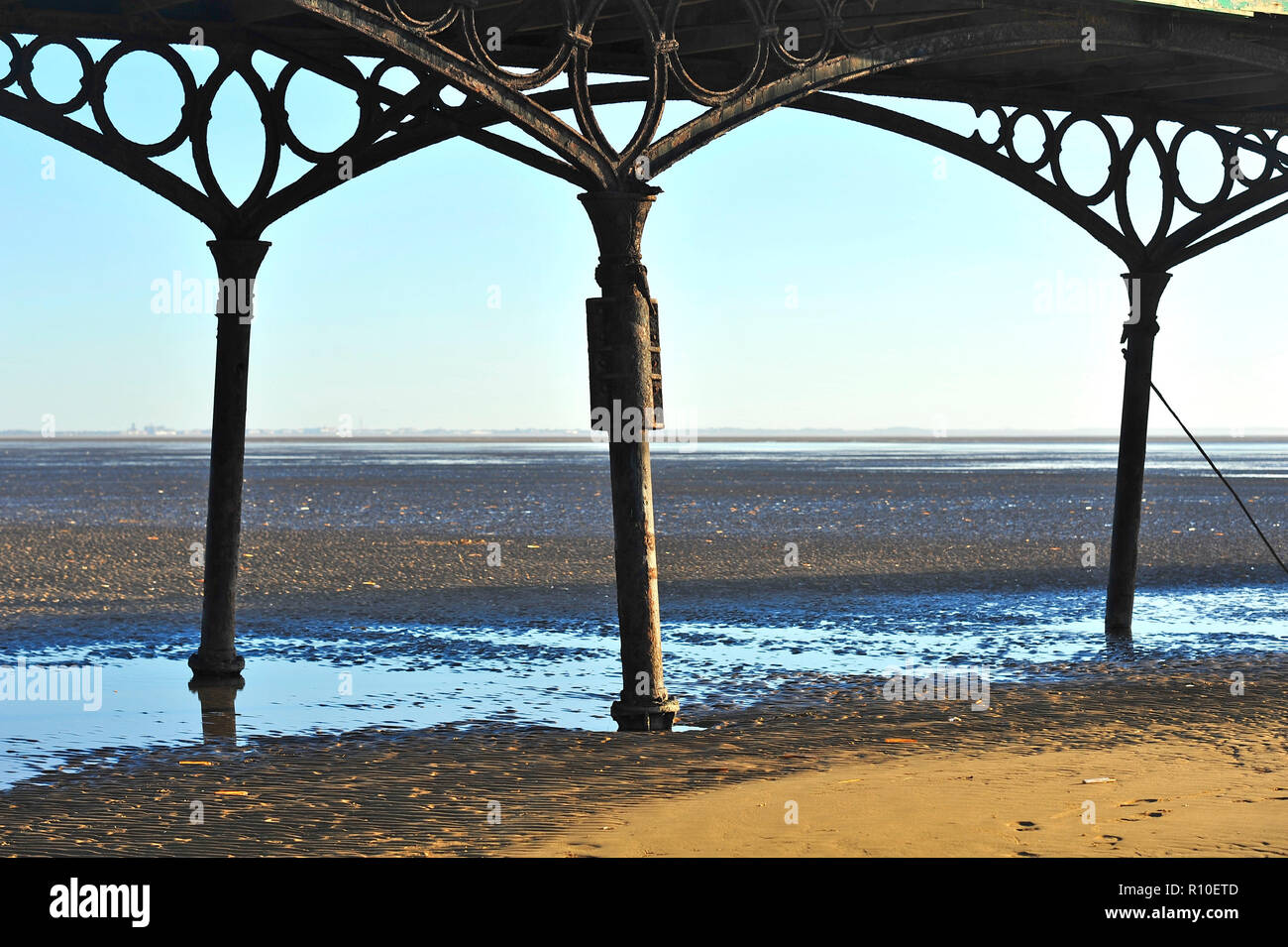 Leaning iron leg supports underneath seaside pier Stock Photo - Alamy