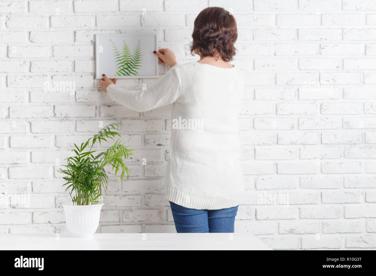 Back of woman hanging her sketch on wall. Female artist evaluate her ...