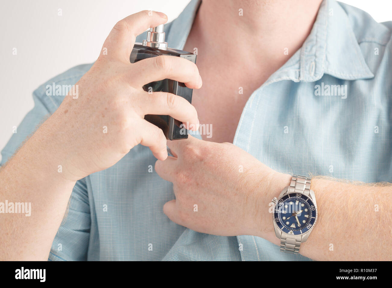 Man applying perfume on his neck on white background Stock Photo - Alamy